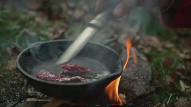 A Man Cooking Meat Over Fire